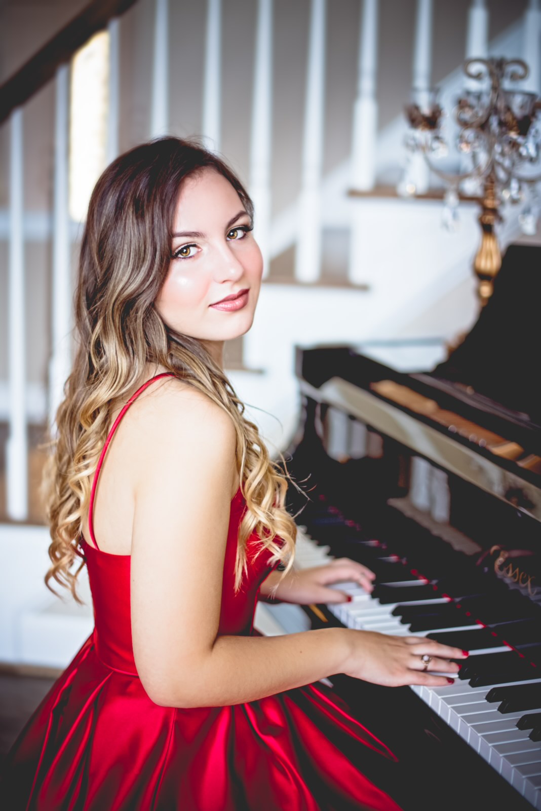 A person in a red dress sitting at a pianoDescription automatically ...